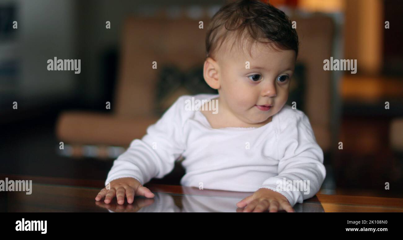 Happy toddler boy standing by table. Joyful infant baby hitting table ...