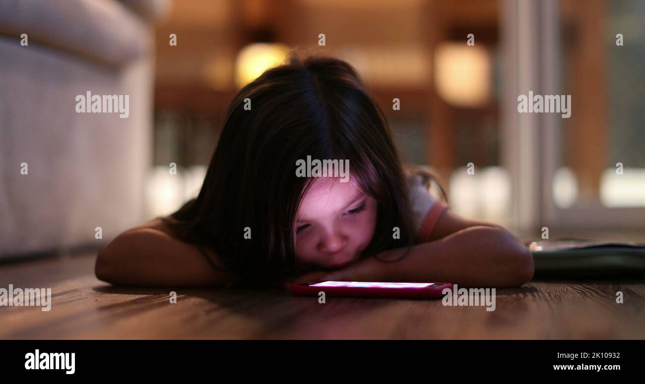 Little girl staring at cellphone screen at night. Child watching ...