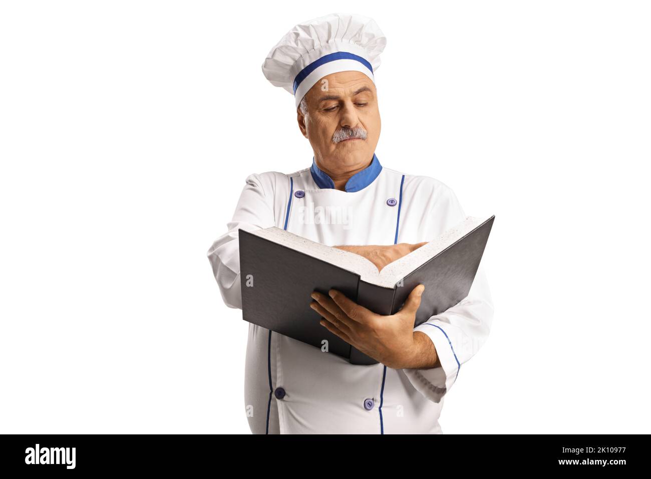 Mature male chef reading from a cook book isolated on white background ...