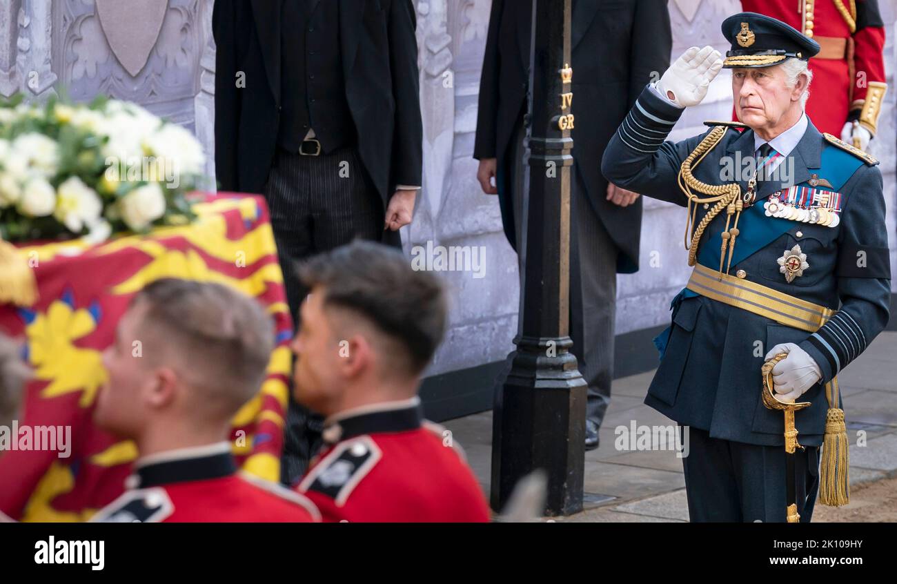 King Charles III, salutes as the bearer party carry the coffin of his ...