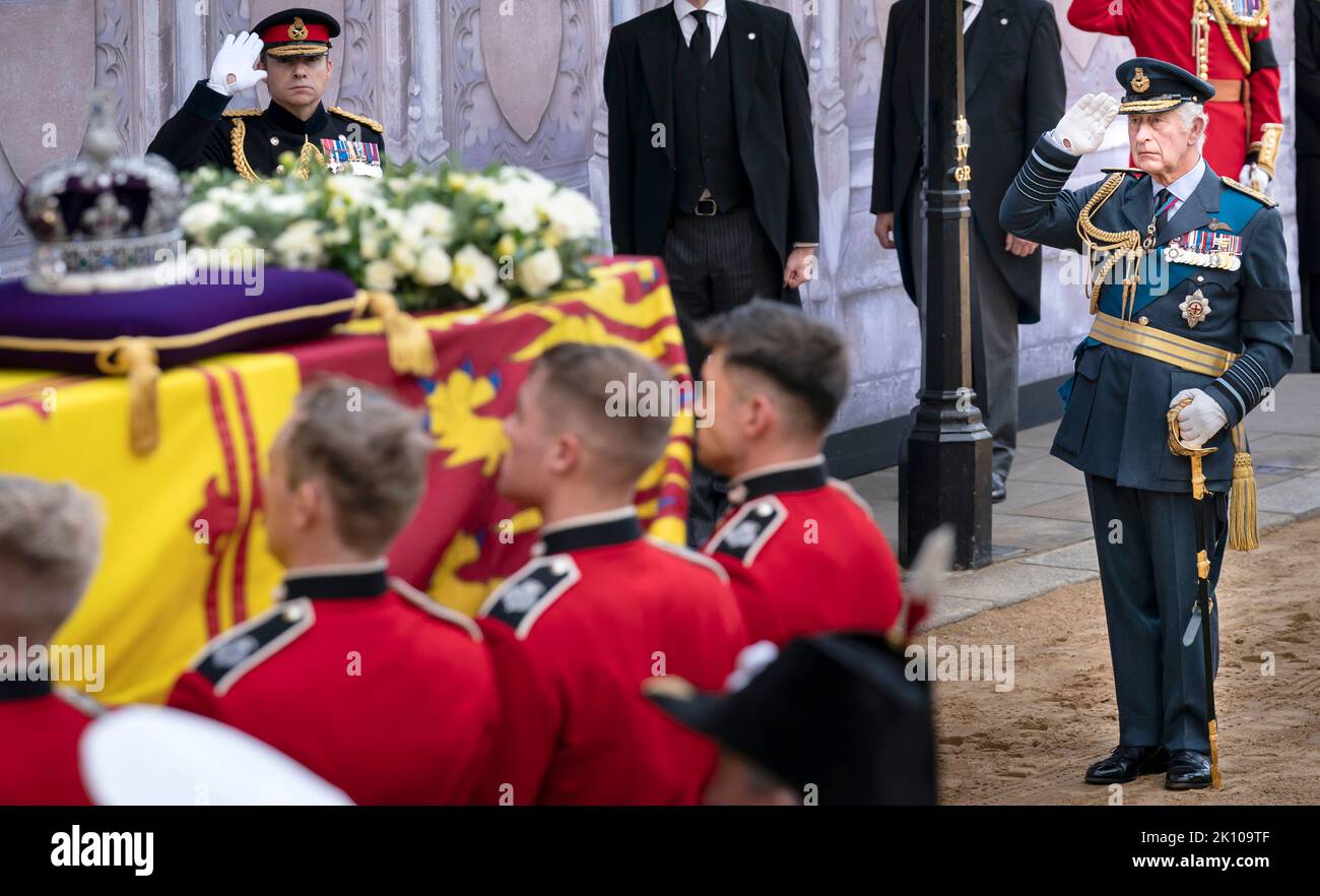 King Charles III, salutes as the bearer party carry the coffin of his ...