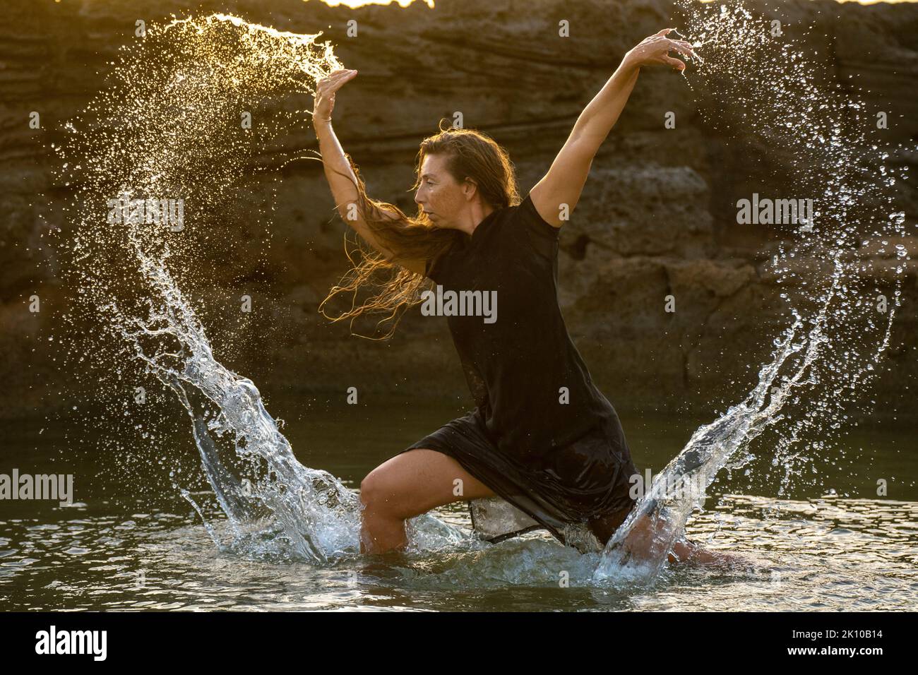 middle-aged woman dancing and throwing water in the air, Maioris beach ...