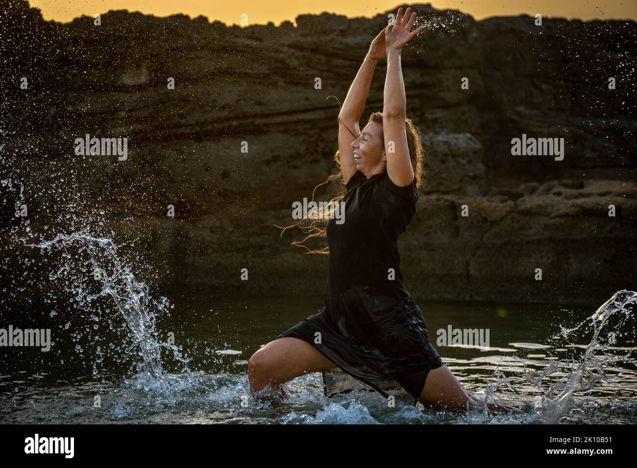 middle-aged woman dancing and throwing water in the air, Maioris beach ...