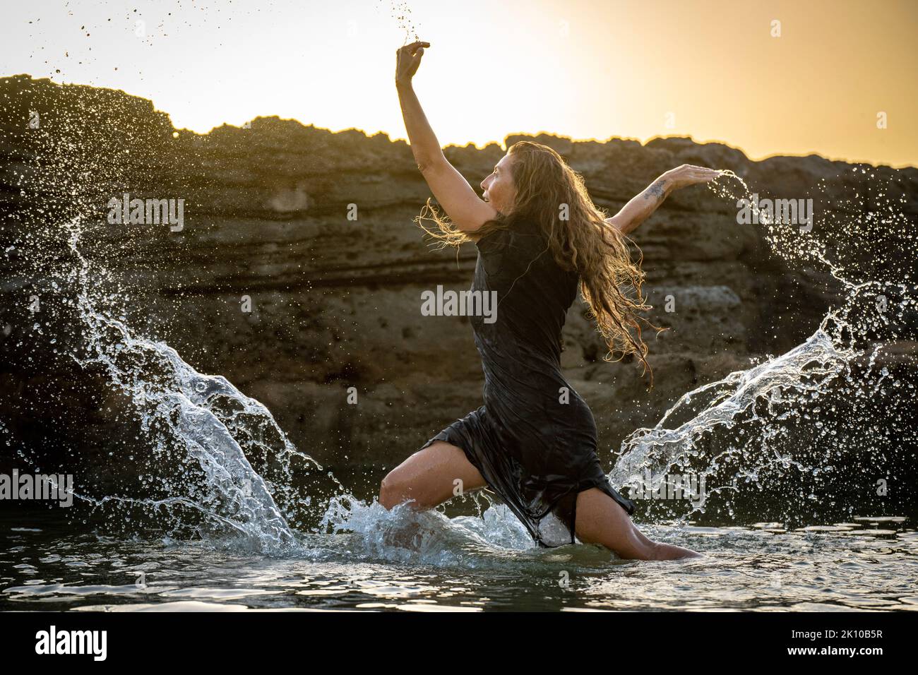 middle-aged woman dancing and throwing water in the air, Maioris beach ...
