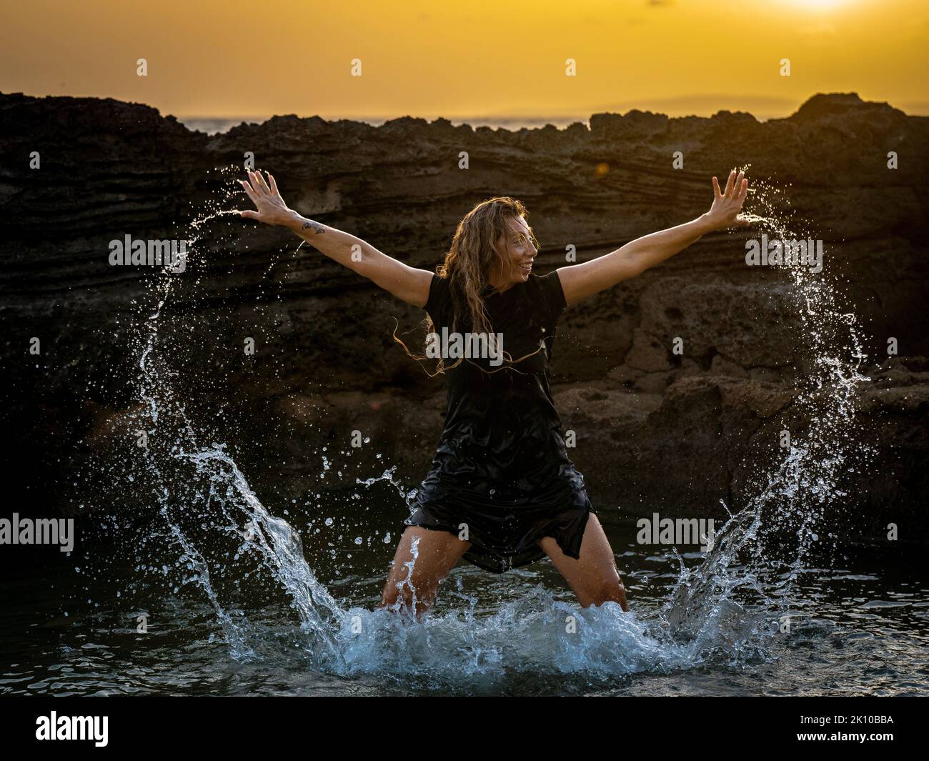 middle-aged woman dancing and throwing water in the air, Maioris beach ...