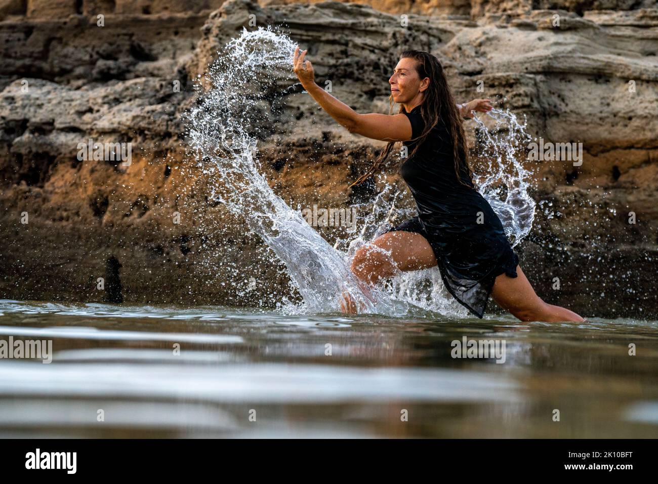 middle-aged woman dancing and throwing water in the air, Maioris beach ...