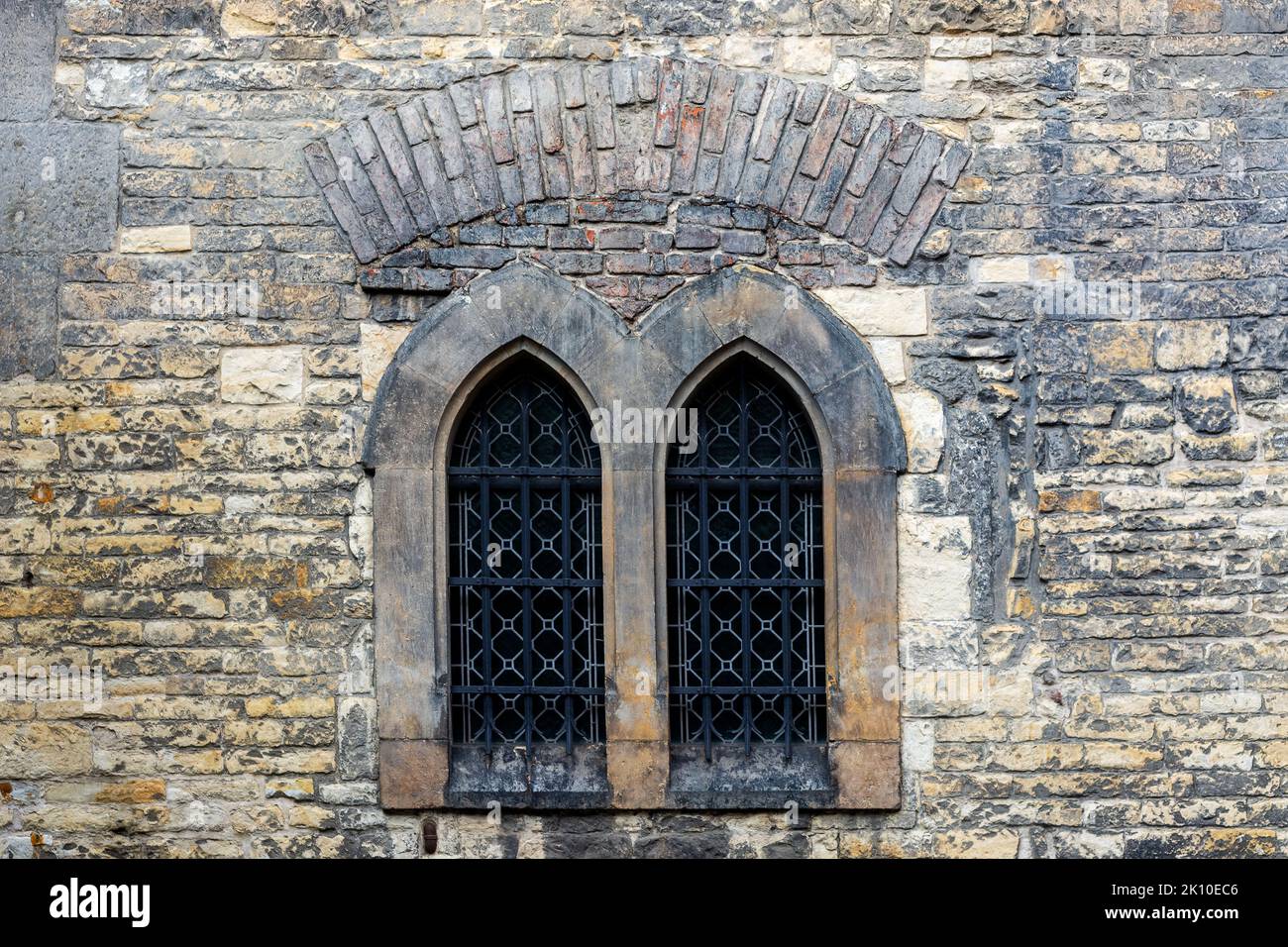 Two arched windows with metal bars on the old fortress wall made of ...