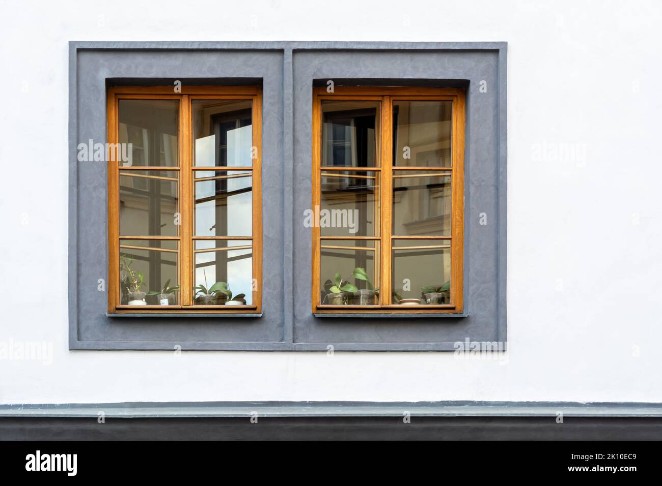 Two rectangular gray windows with brown wooden frames against a white ...