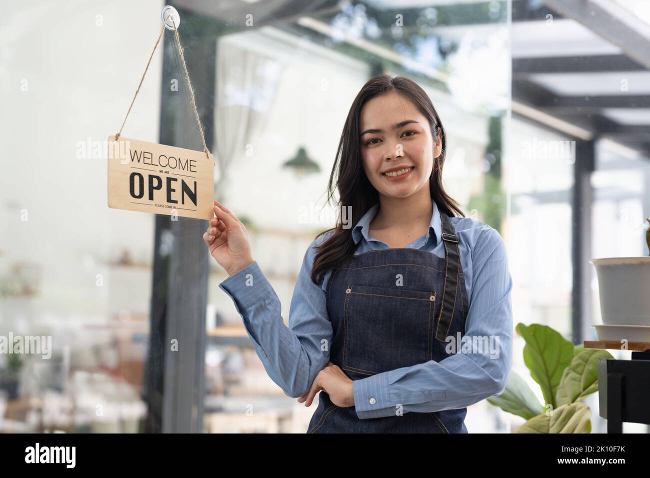 Young Asia manager girl changing a sign from closed to open sign on ...