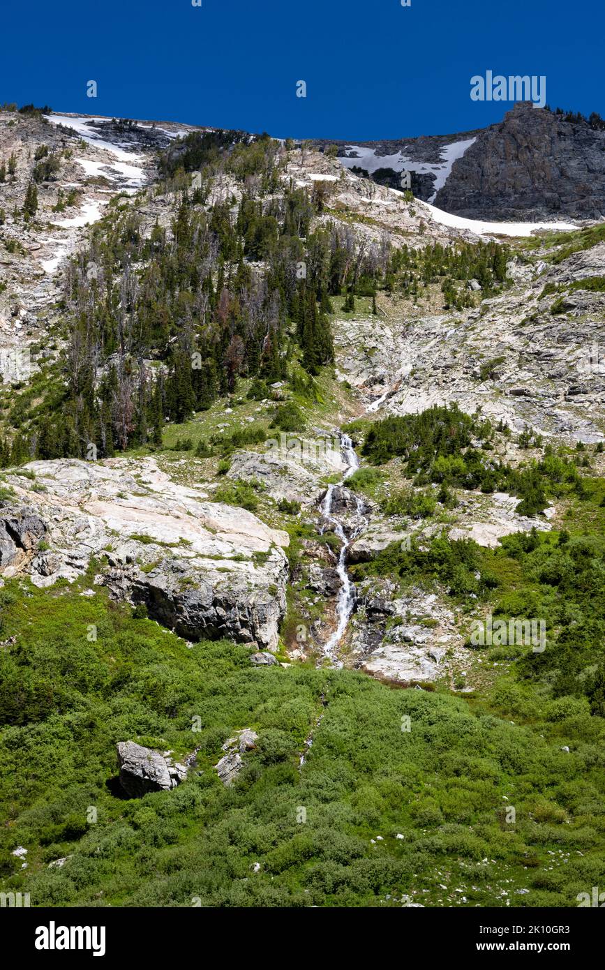 A large waterfall pouring over the rocky cliffs of the higher elevations of Open Canyon. Grand ...