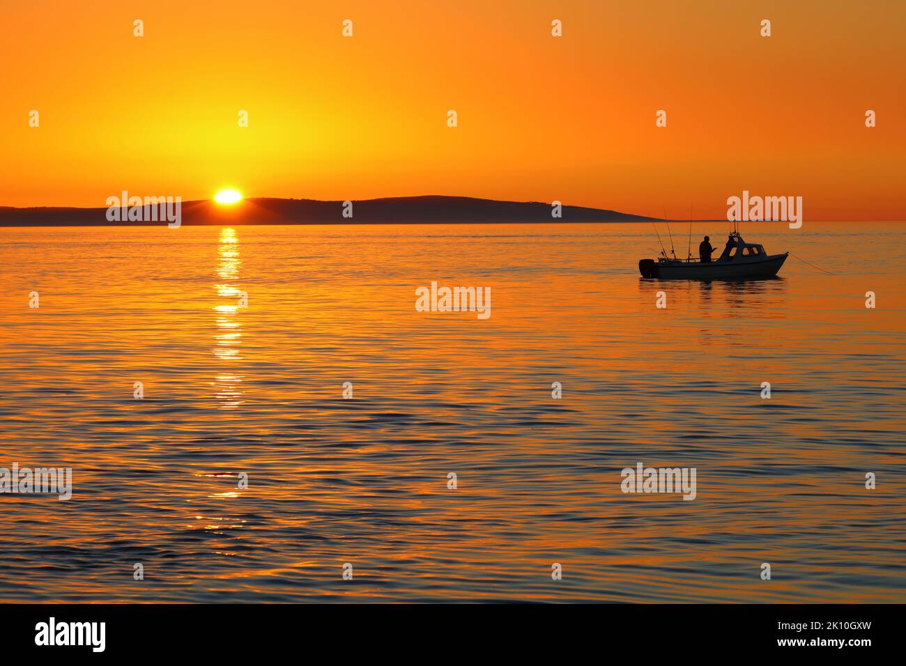 Gorgeous Orange Sunset with silhouette of small boat and Isle of ...