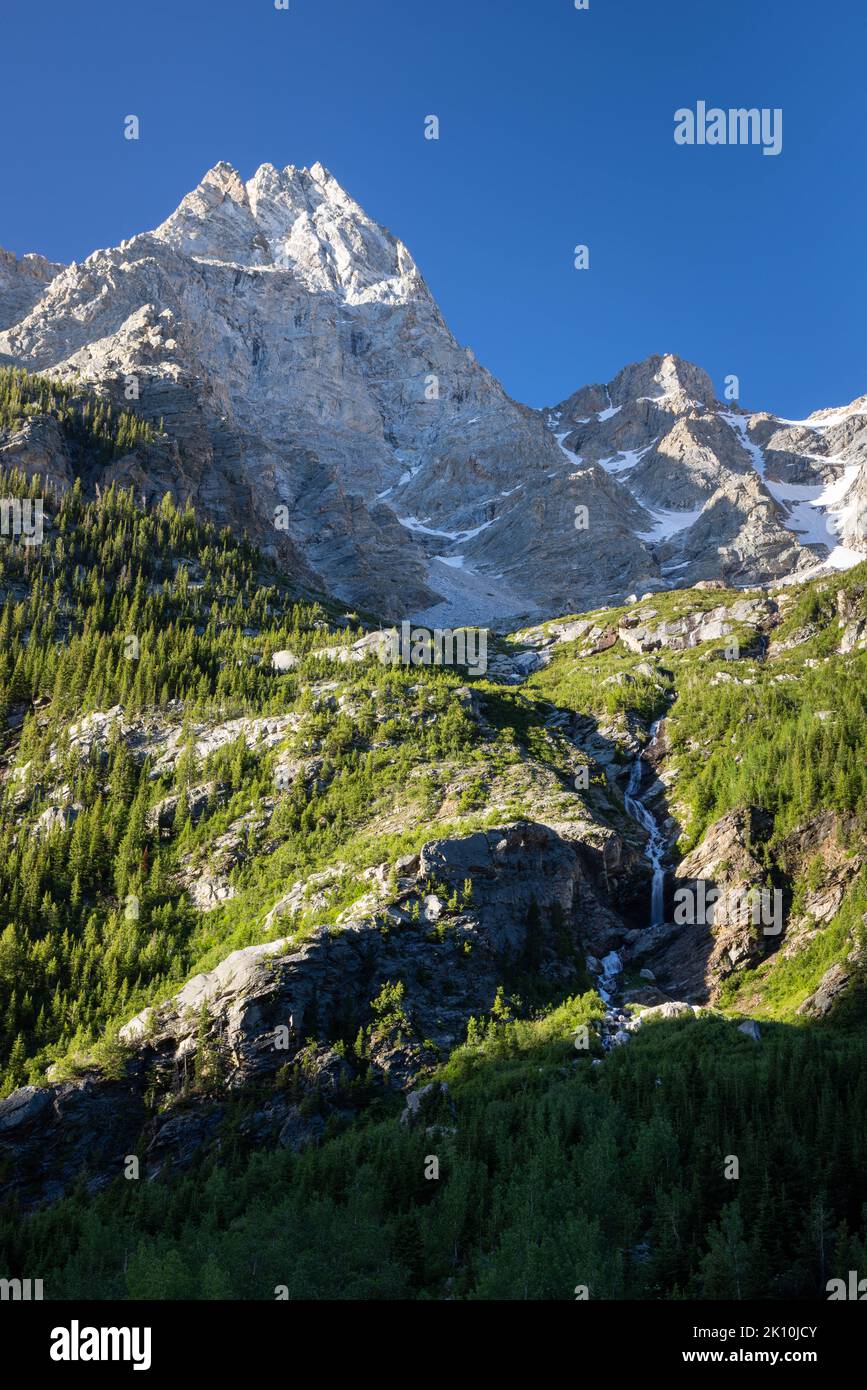 A waterfall pouring over the cliffs below alpine peaks lining the walls of Cascade Canyon. Grand ...