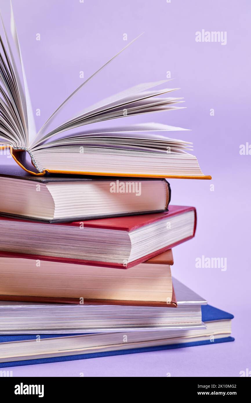 Close-up of a stack of books with one open book on top Stock Photo - Alamy