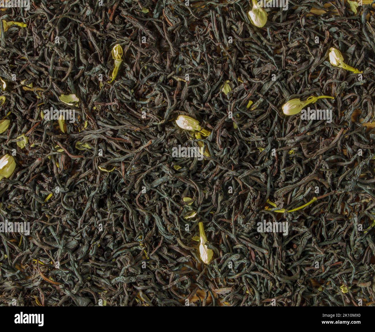 Background of fragrant black tea leaves with dried jasmine flowers. Dry ...