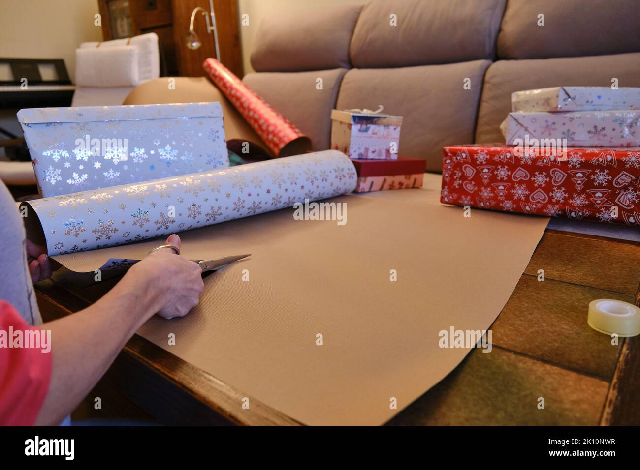 A Unrecognizable woman cutting out Christmas paper to wrap presents ...
