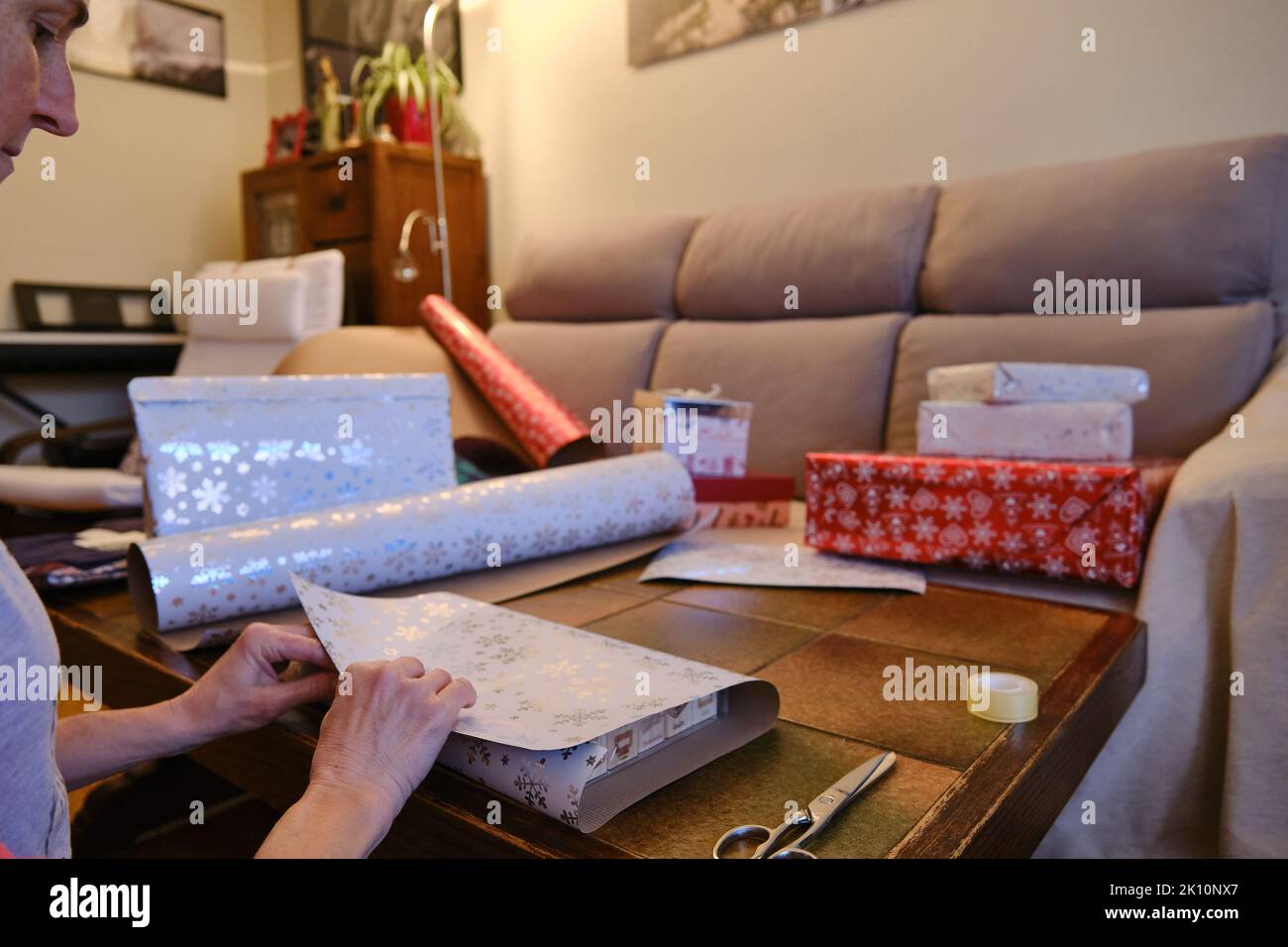 A Woman cutting out Christmas paper to wrap presents Stock Photo - Alamy