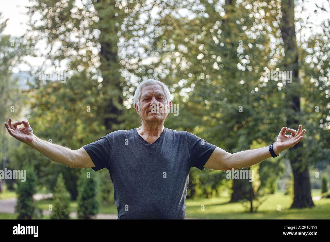 Older hoary man close eyes makes mudra gesture start new day with wok ...