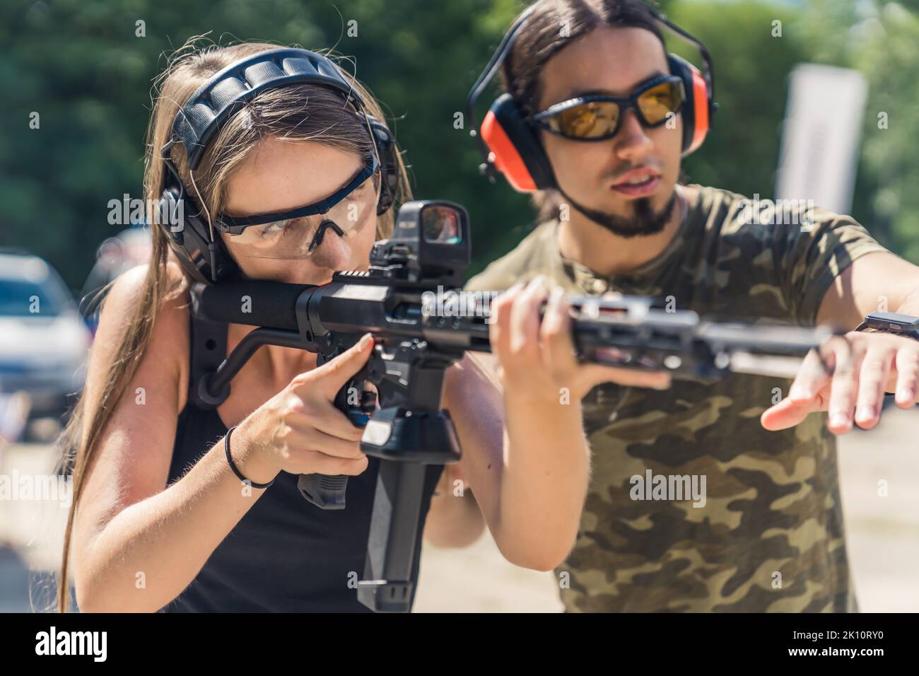 long-haired girl practicing target shooting with an instructor and ...