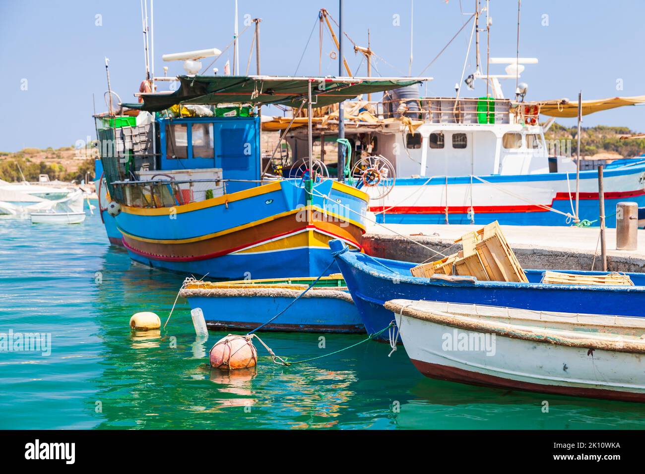 Colorful traditional Maltese fishing boats are moored in Marsaxlokk ...