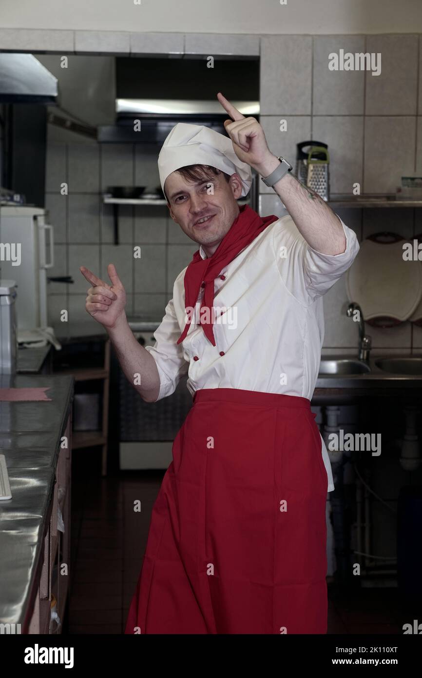 Young happy man dressed as chef dancing in kitchen in restaurant. Male ...