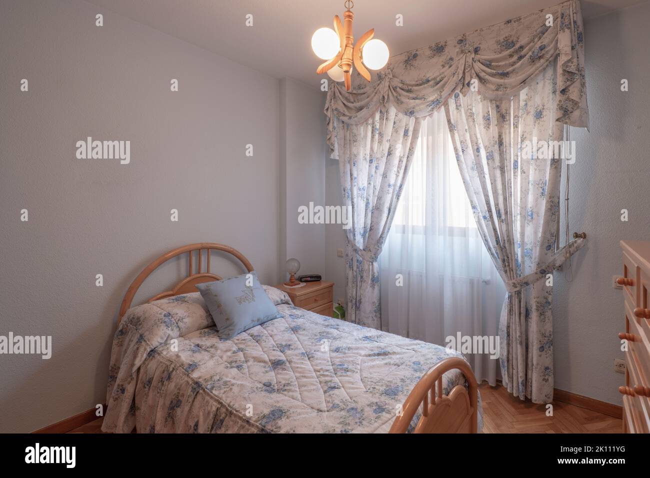 bedroom with a single bed with wooden furniture, a window with flowery ...