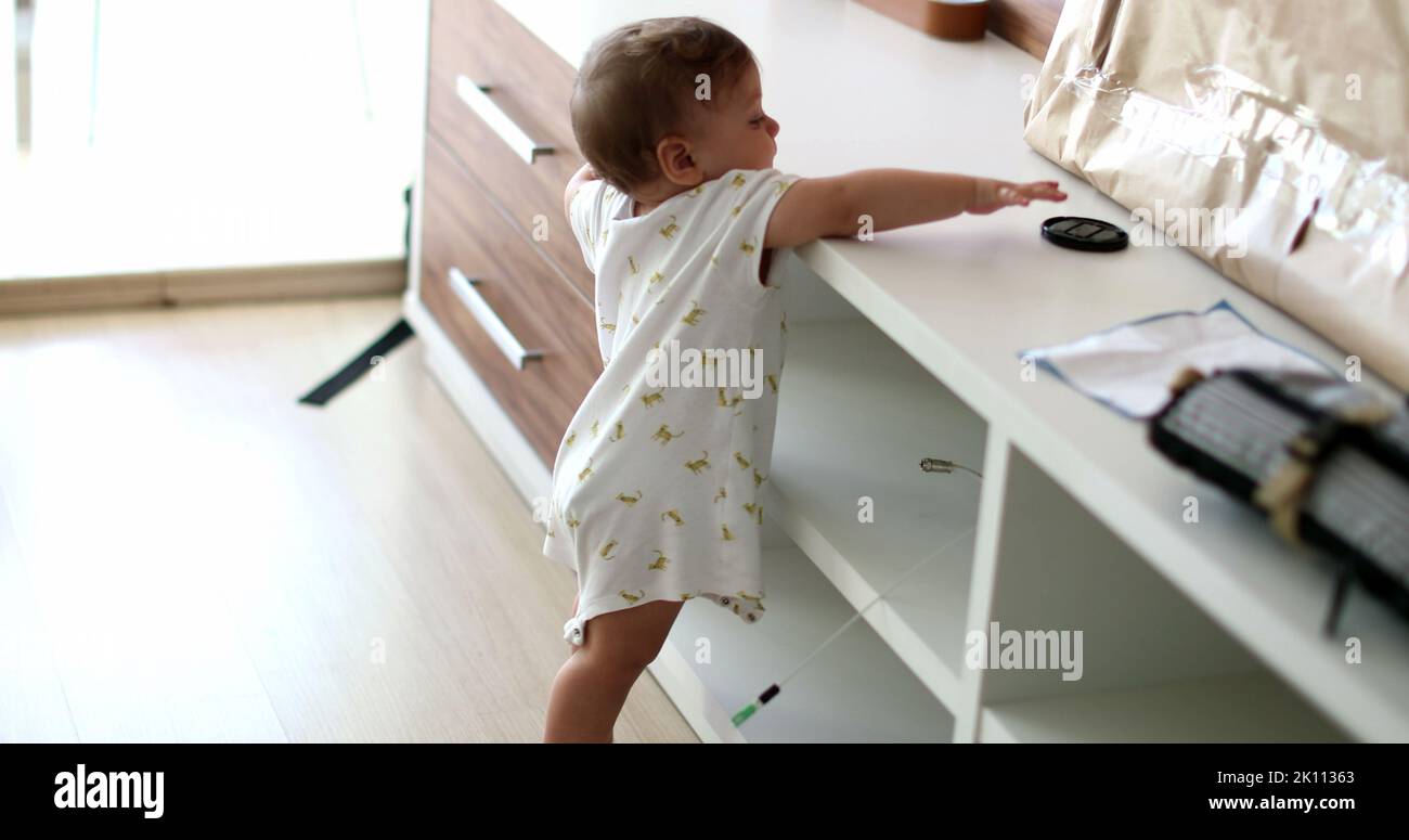 Baby standing leaning on furniture at home living-room. toddler ...