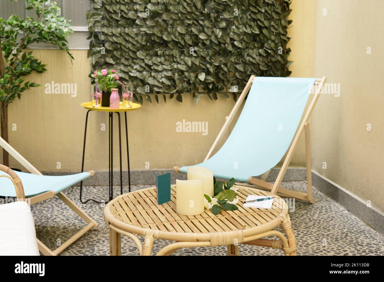 Corner of a terrace with wicker furniture, matching side table and ...