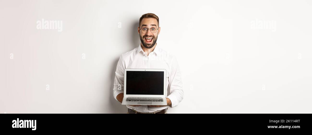 Excited businessman showing something on laptop screen, standing happy ...