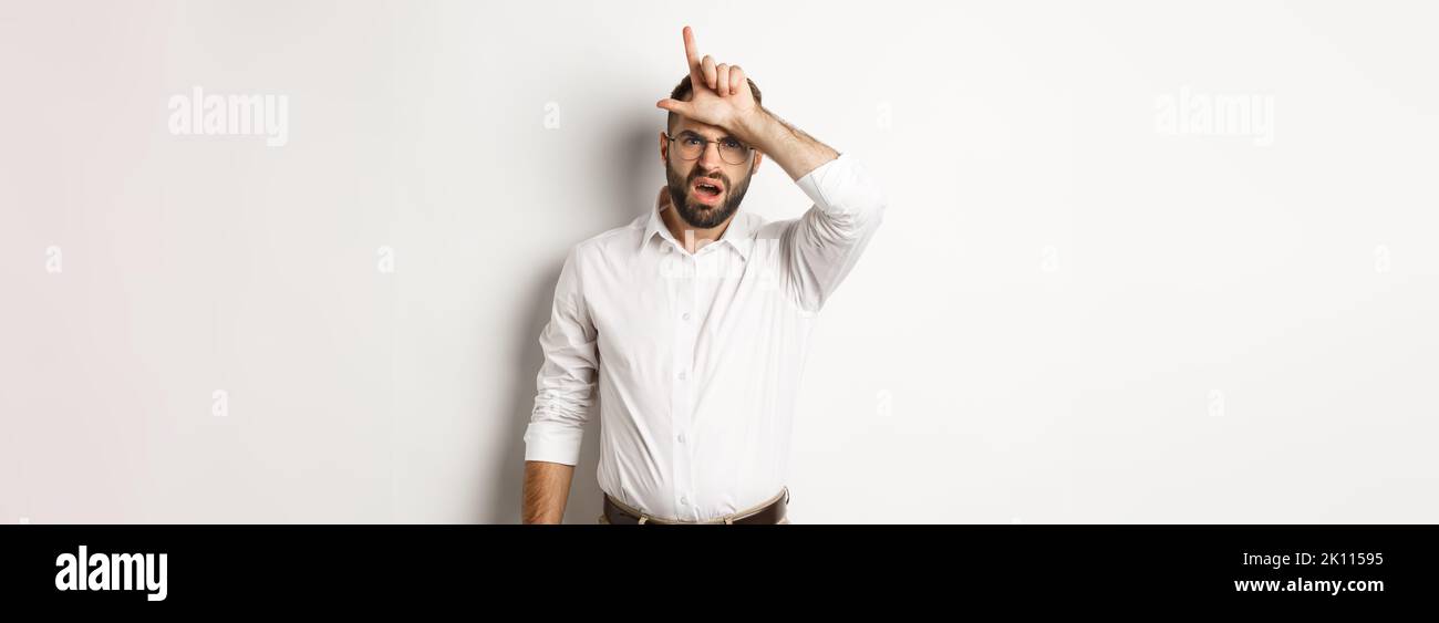 Shocked guy showing loser sign on forehead, complaining, standing over ...