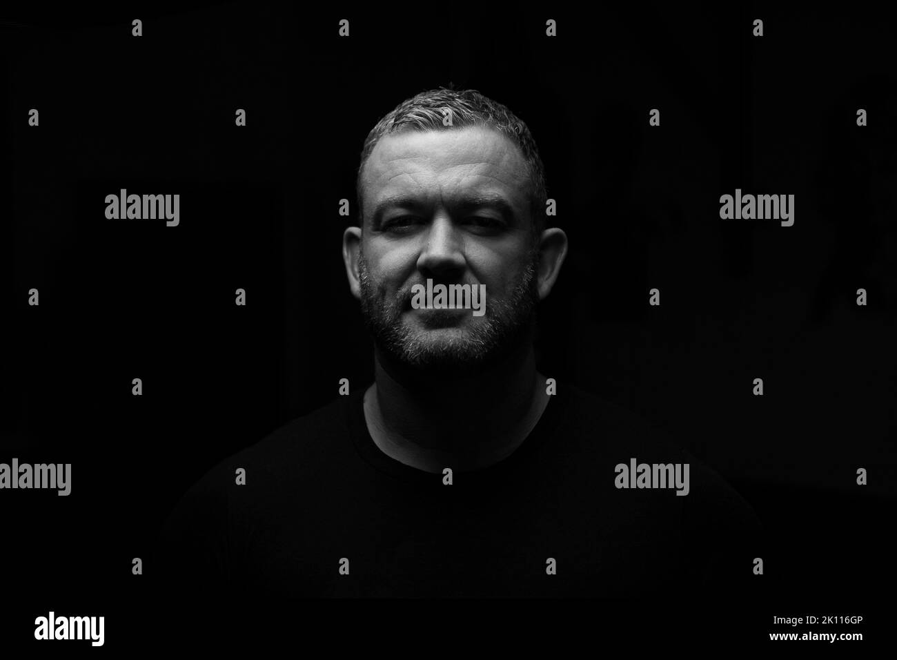 Adults male in darkness and looking into camera Stock Photo - Alamy
