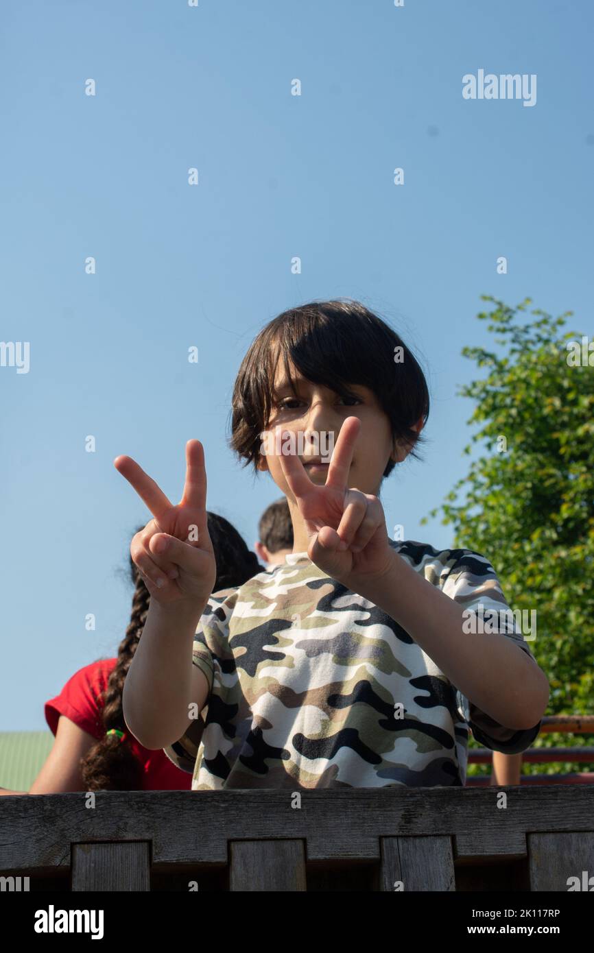 Portrait of little boy showing victory hand sign Stock Photo - Alamy