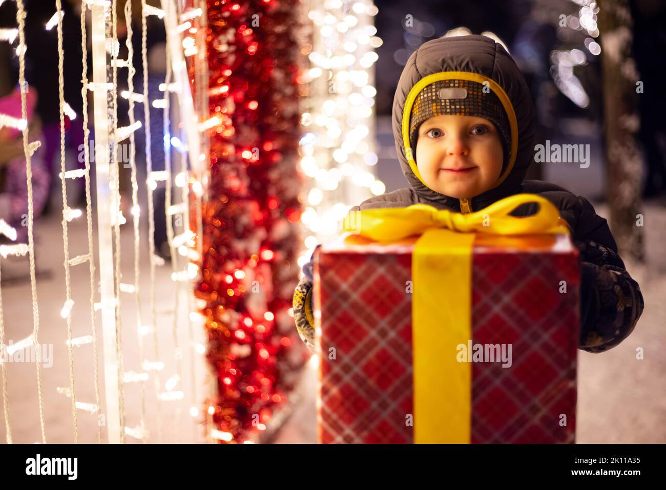 Happy child in a red Santa Claus hat with wrapped Christmas gift Stock ...