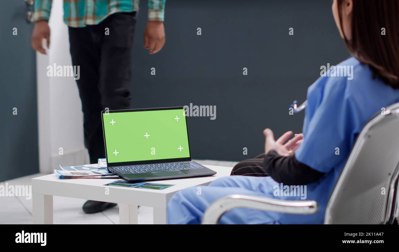 People sitting in waiting area with greenscreen template on laptop ...