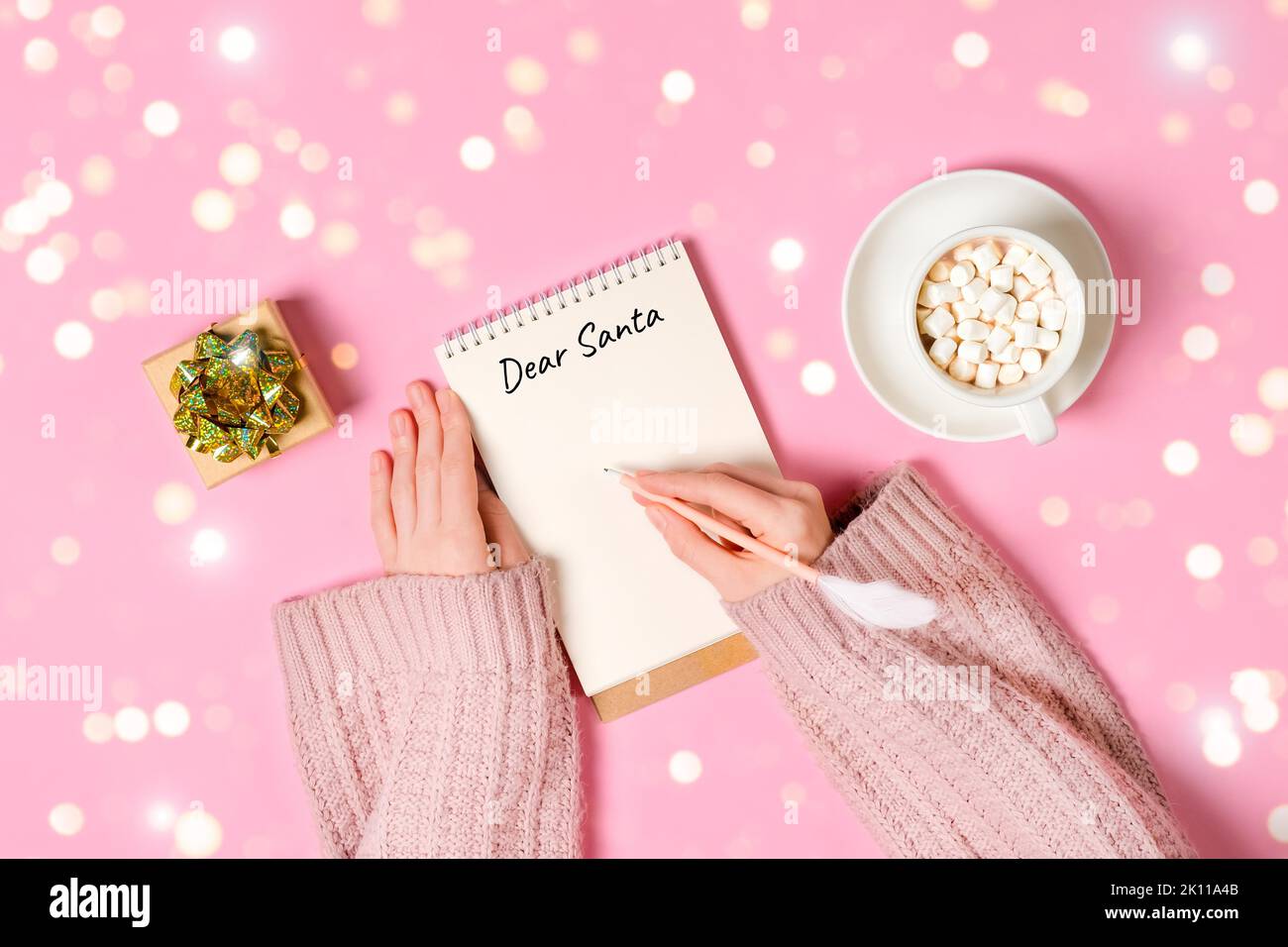 Letter to Dear Santa. Hand holding pink pen decorated with feather and ...