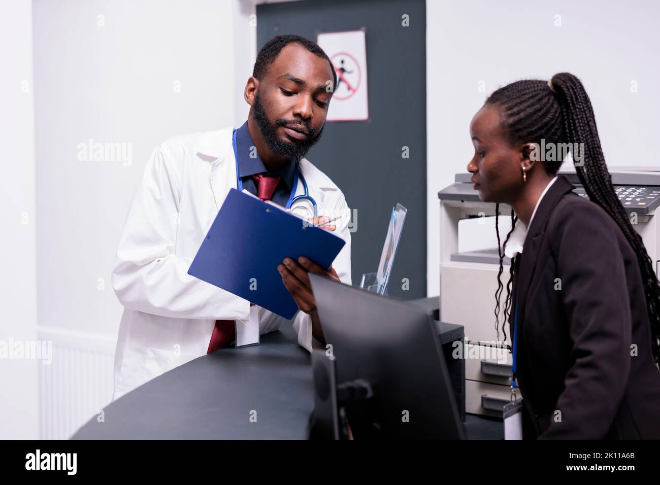 African american staff working on medical reports at hospital reception ...