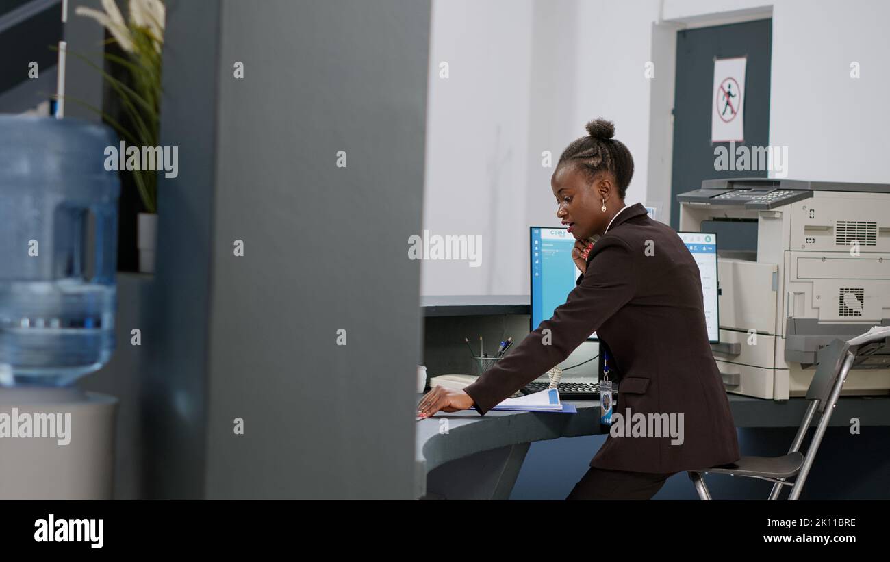 Medical worker answering landline phone call at reception desk counter ...