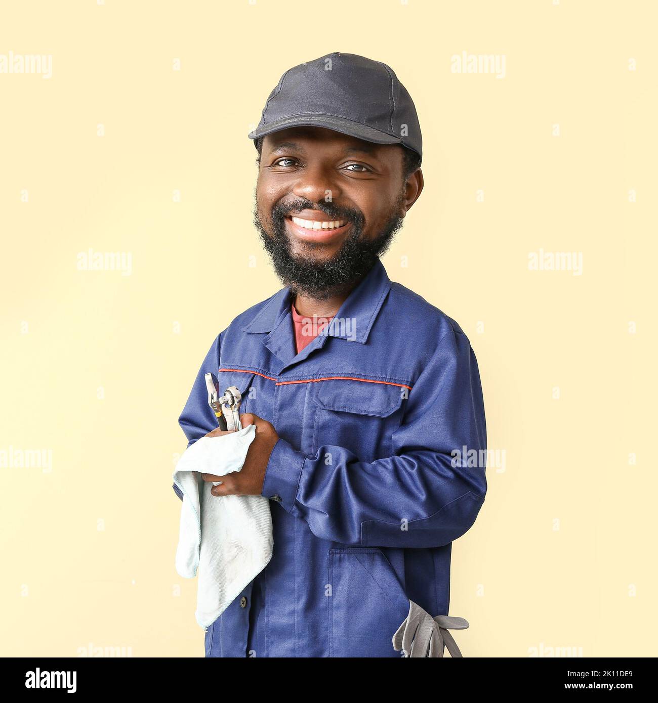 Funny African-American car mechanic with big head on beige background ...