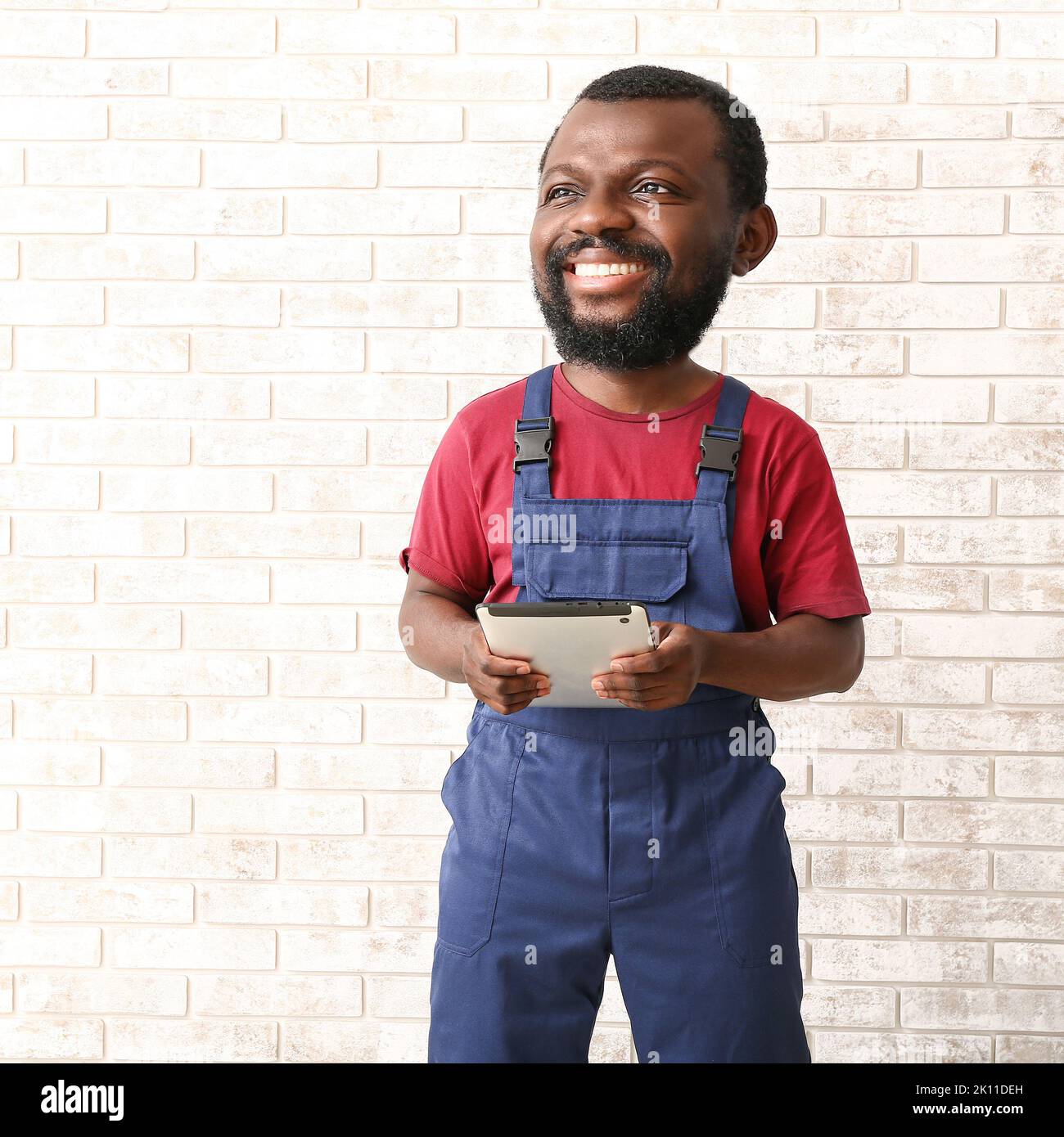Funny African-American car mechanic with big head holding tablet ...