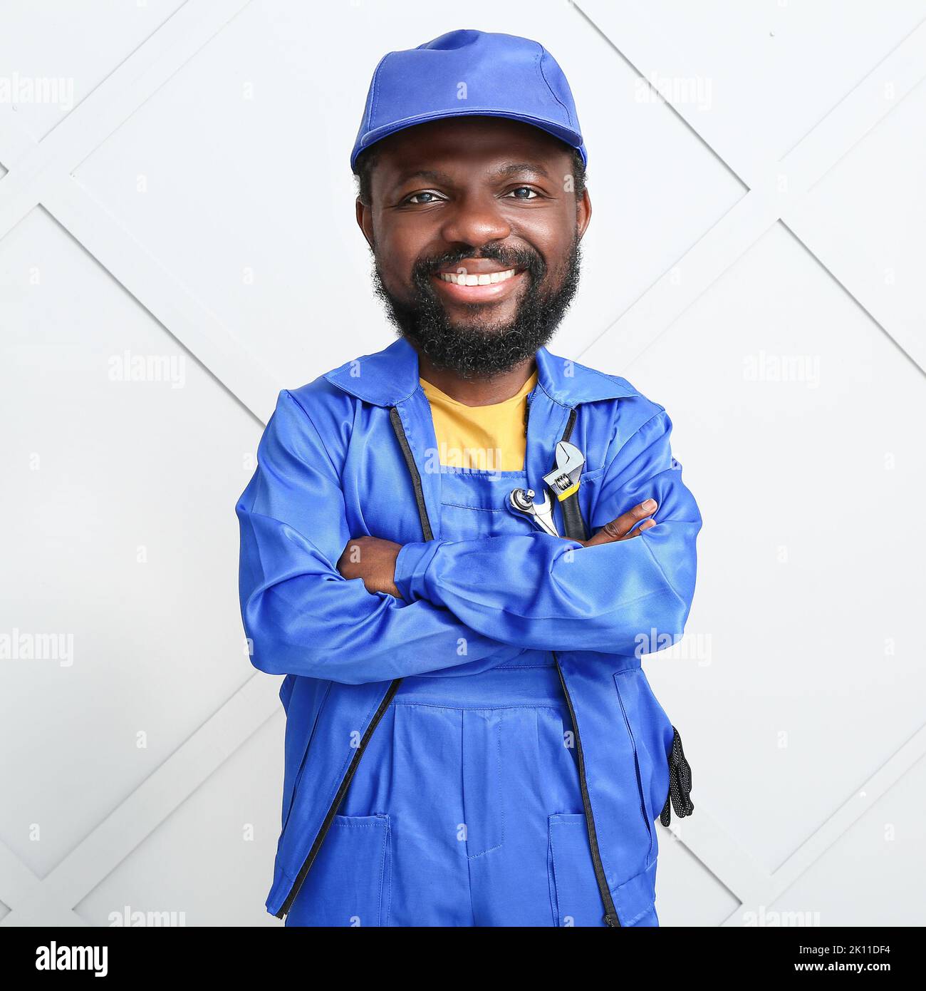 Funny African-American car mechanic with big head on light background ...