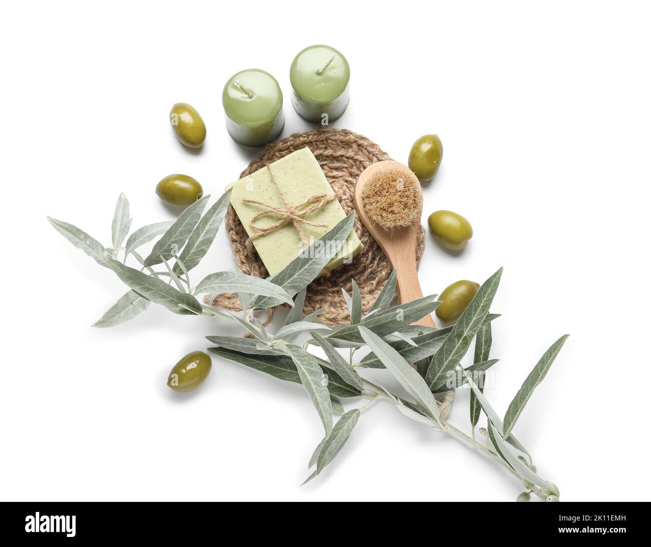 Olive soap bar, candles, massage brush and tree branch on white ...