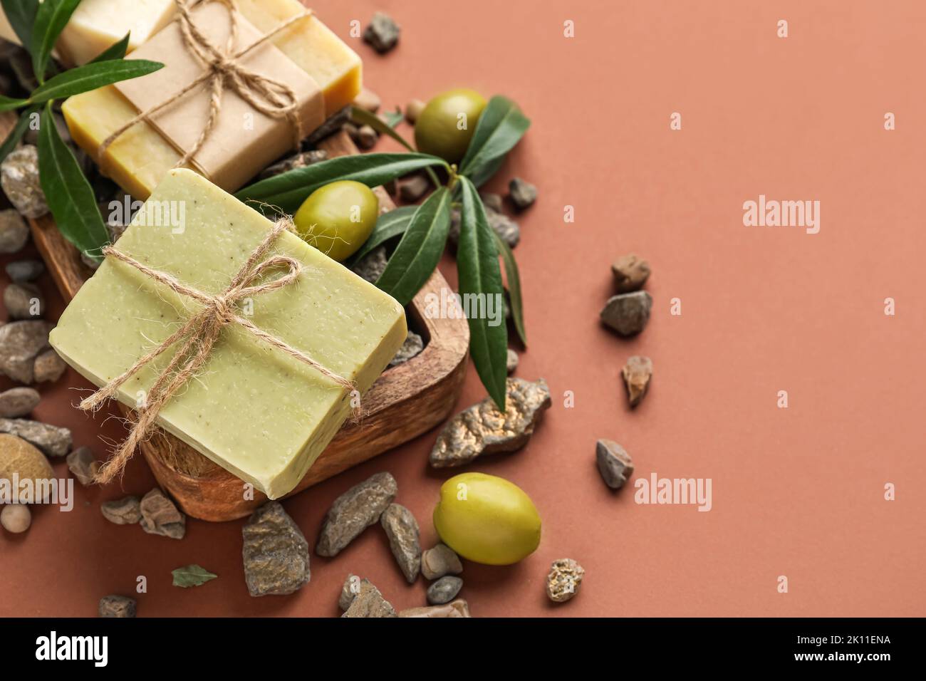 Board with olive soap bars and stones on color background, closeup ...