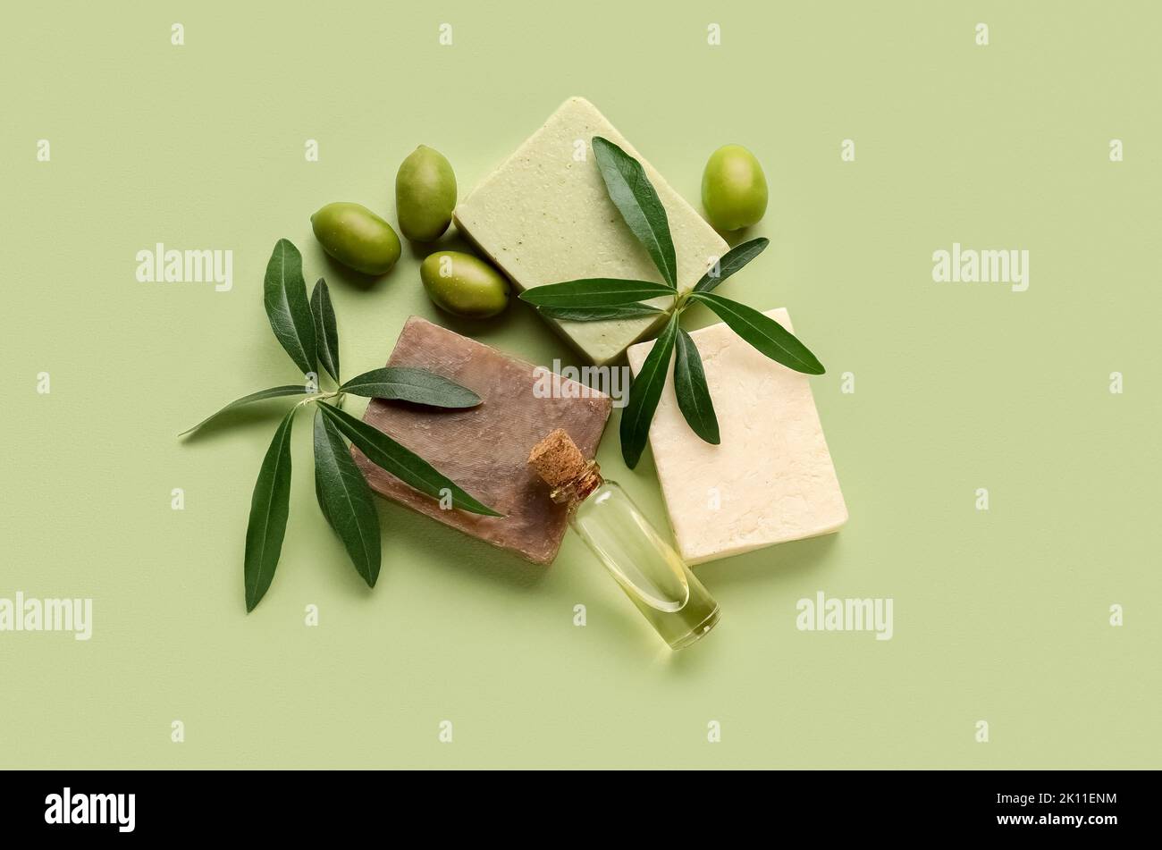 Olive soap bars and bottle of essential oil on color background Stock ...
