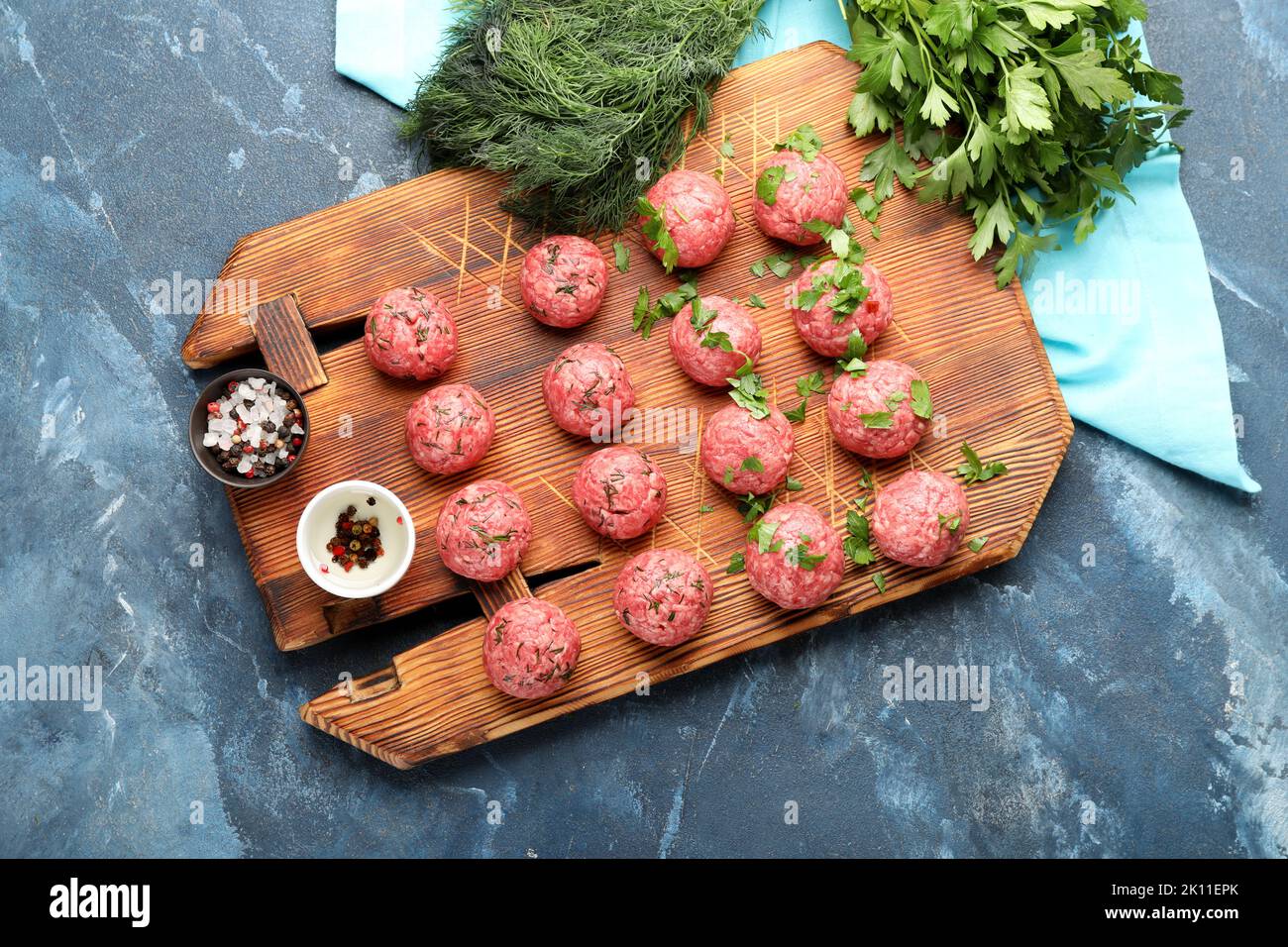 Wooden board with raw meat balls, herbs and spices on grunge background ...