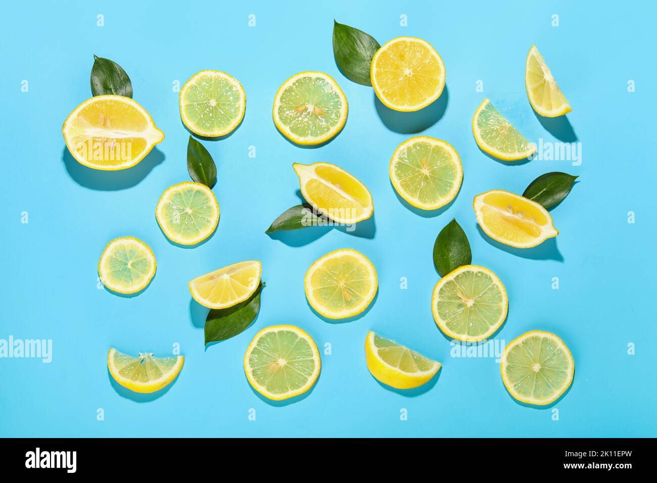Slices of fresh lemons and leaves on color background Stock Photo - Alamy