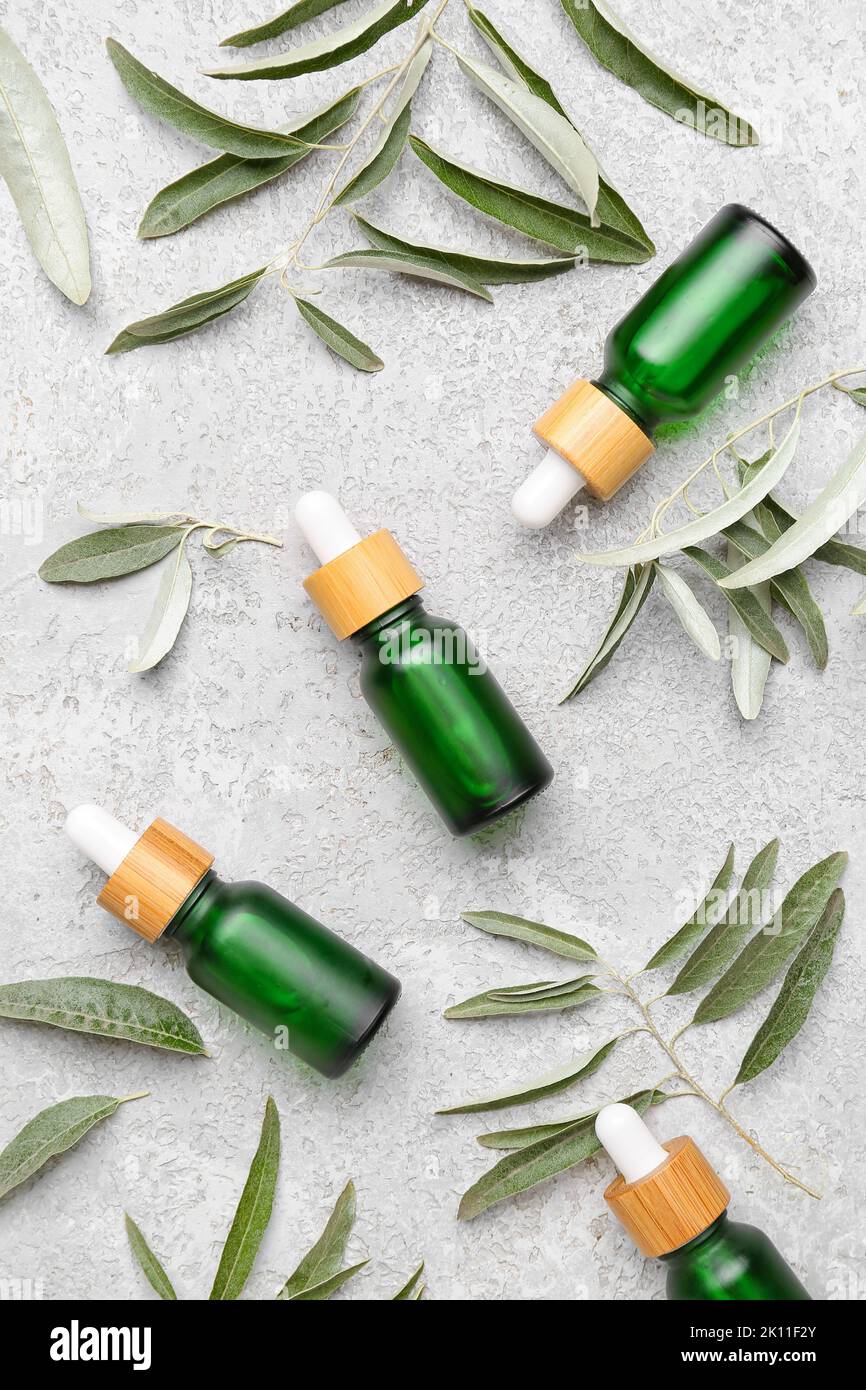 Composition with bottles of essential olive oil and plant leaves on ...