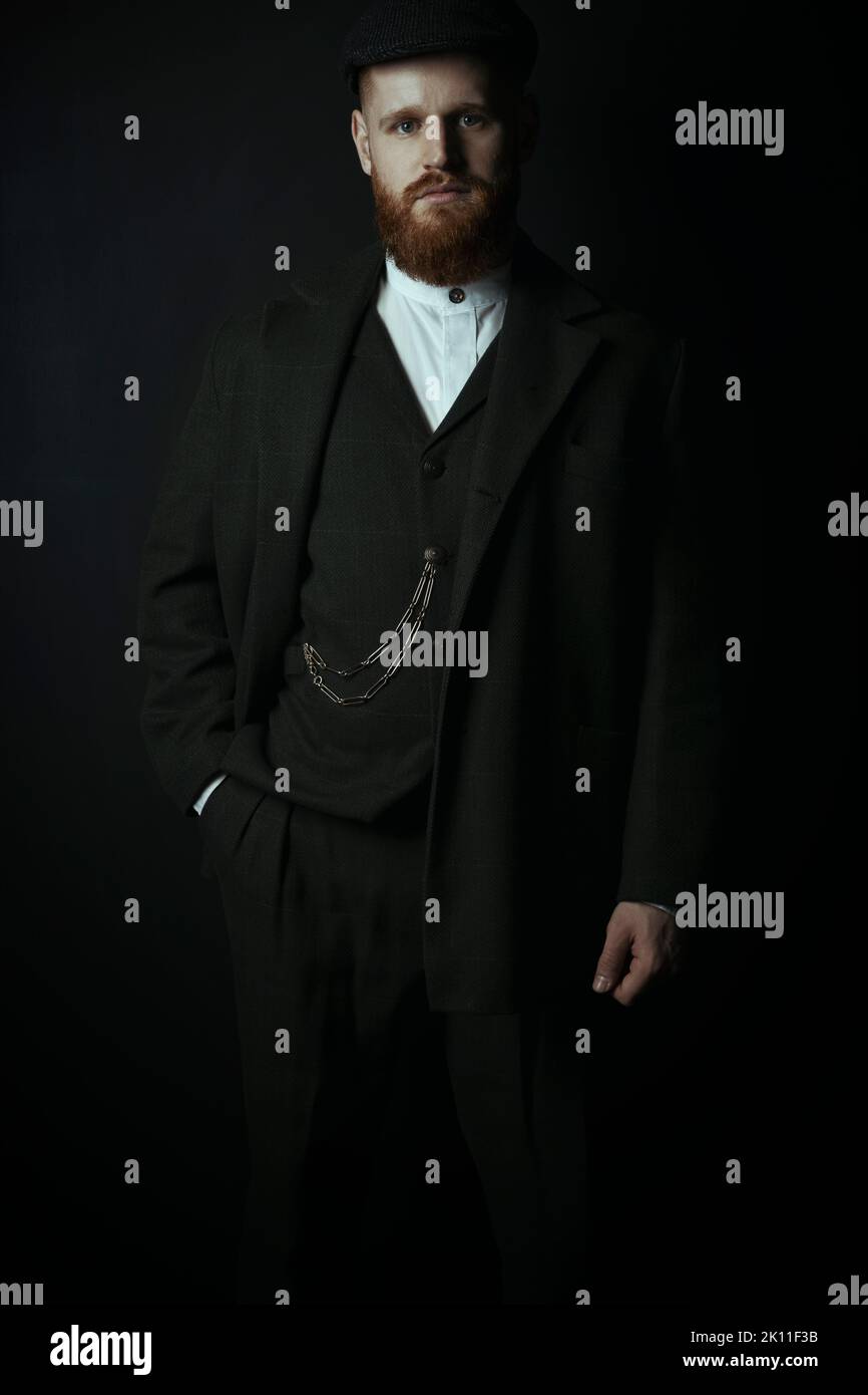 A working class Victorian man with red hair and beard against a black ...