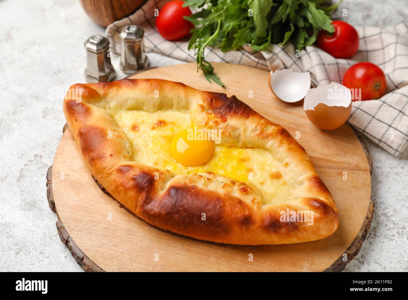 Wooden board with delicious Ajarian khachapuri on light background ...