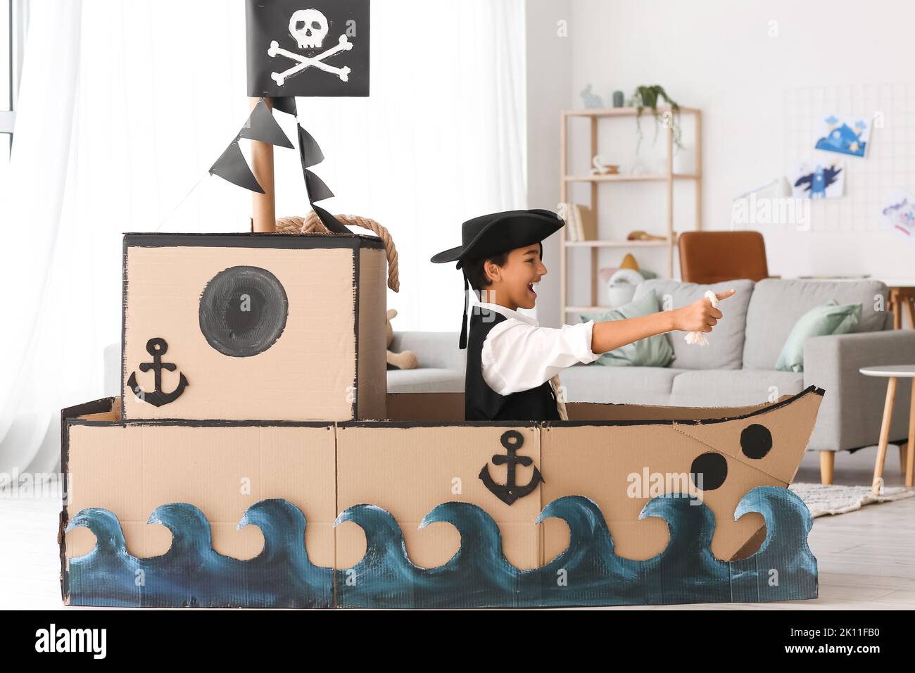 Little boy dressed as pirate playing with rope in cardboard ship at ...