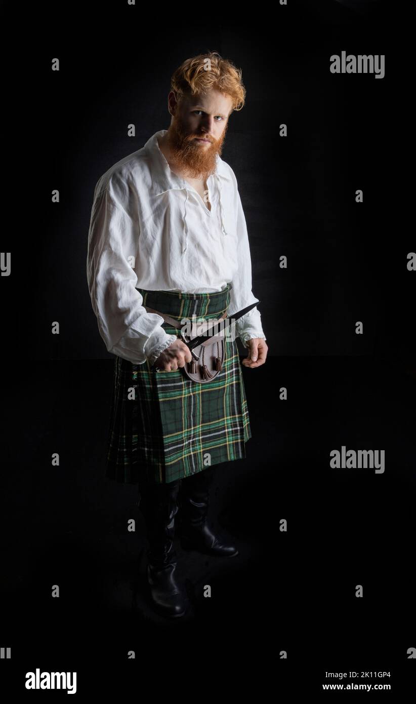 A Scottish man with red hair and beard wearing a kilt and holding a ...