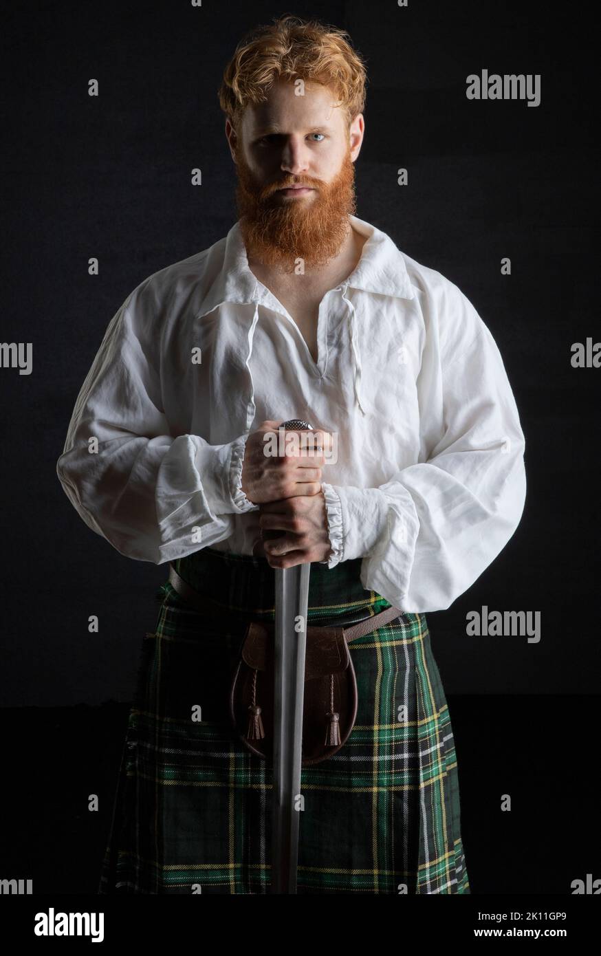 A Scottish man with red hair and beard wearing a kilt and holding a ...